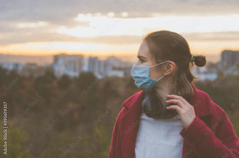 Side view of a woman wearing a face mask and headphones around neck ...