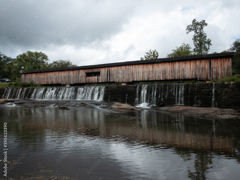 Old wooden bridge right above a small dam and some water flowing over ...