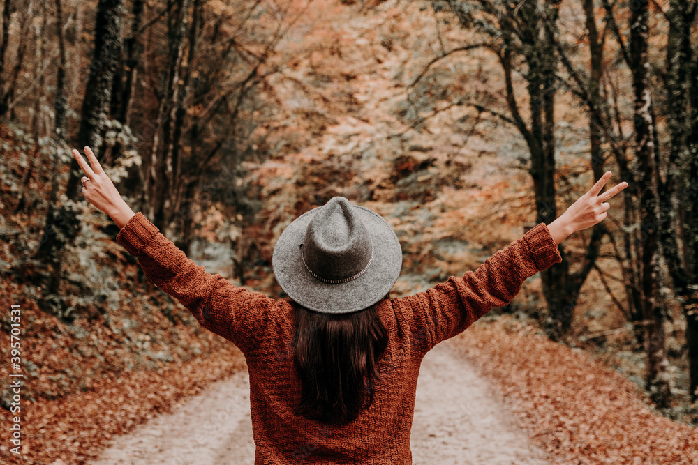 Female with open arms wearing a brown jacket with a fedora hat in a ...