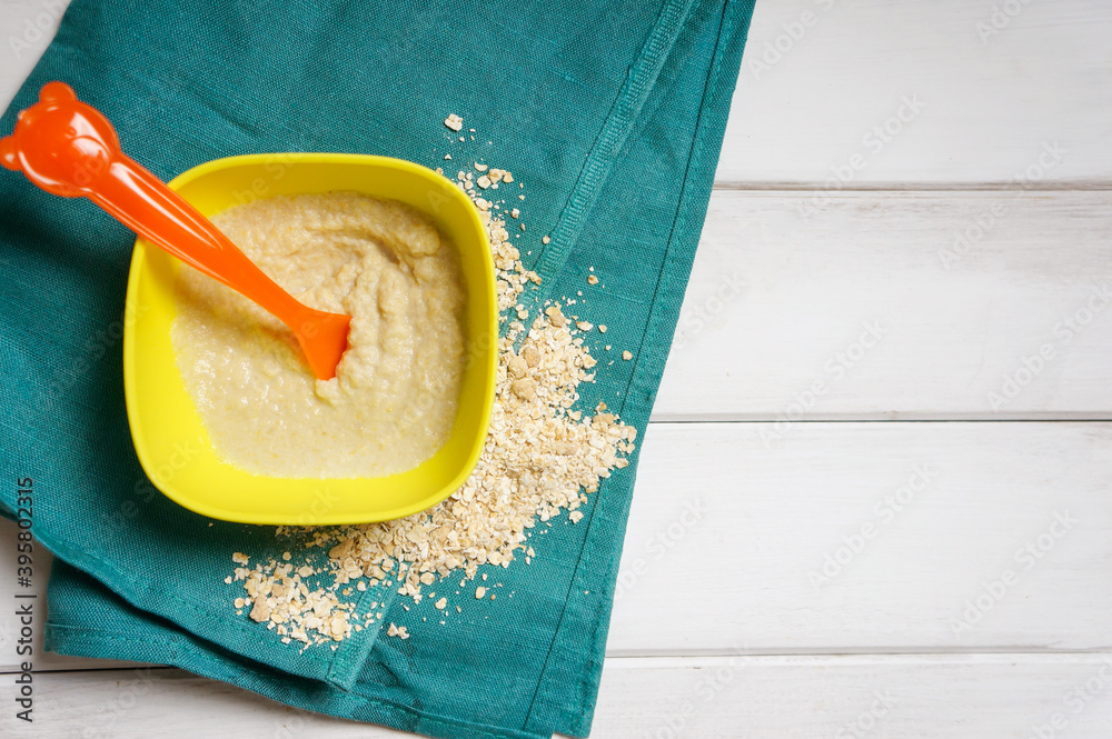 baby oatmeal puree in a bright light green silicone plate with a spoon ...