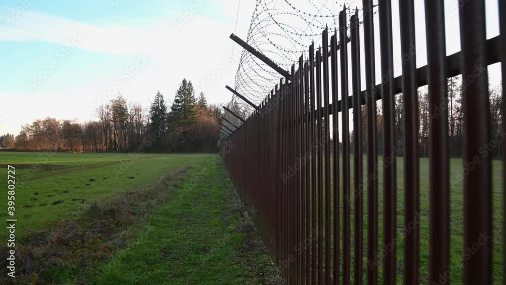 Walking next to steel fence with barb wire on top. Army protected base ...