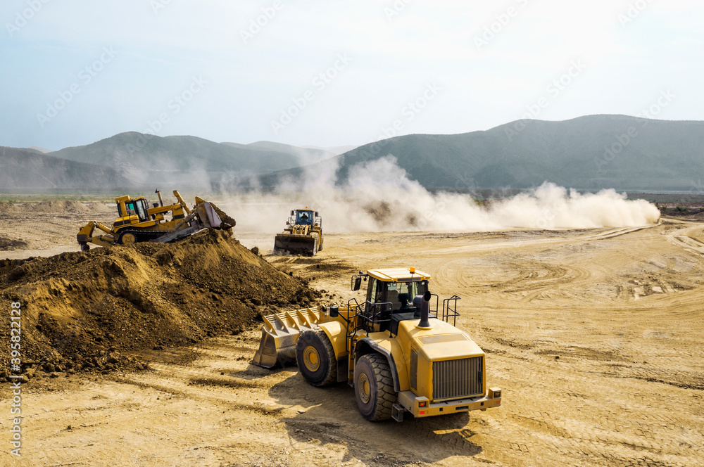Earthworks on a summer day in a mountainous area. Wheel loaders ...