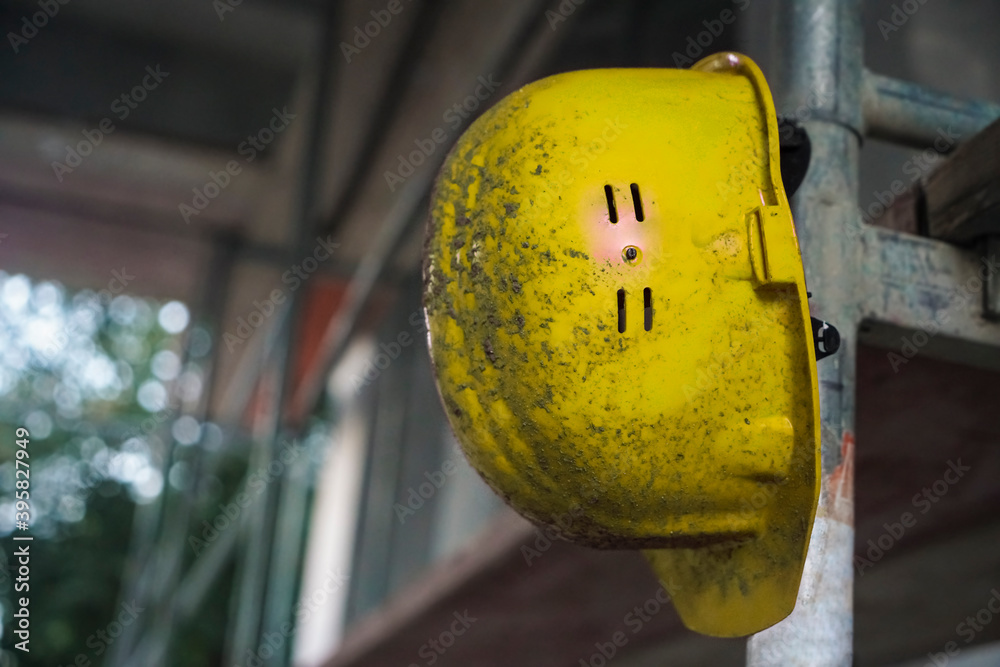 old yellow hard hat hanging on metal scaffolding with blurred ...