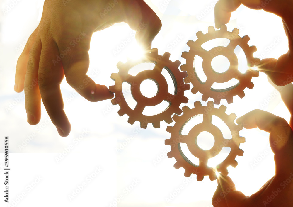 Male hand holding three wooden cog gear wheel on sunny sky background ...