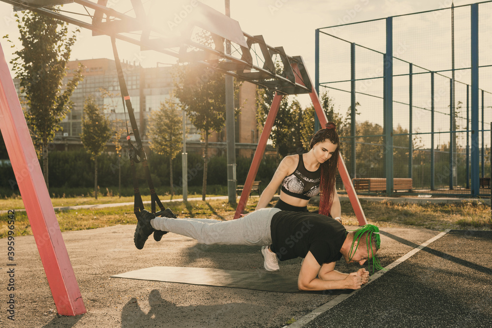 Foto de Woman trainer with braids hairstyle helping man man with mohawk ...