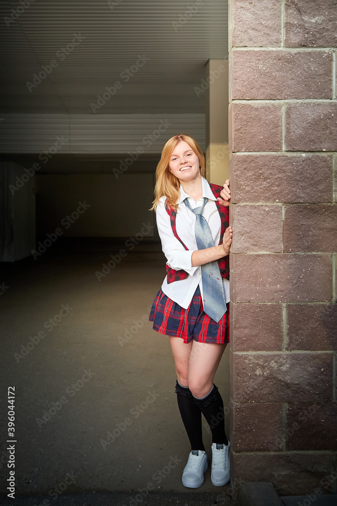 Young girl with short hair in a school checkered uniform outdoors ...