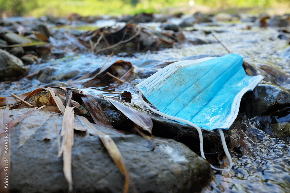 Littered and floating used surgical face mask garbage on a river. Water ...