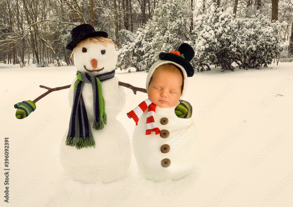 Sleeping baby posing as a snowman next to a real one in a winter ...