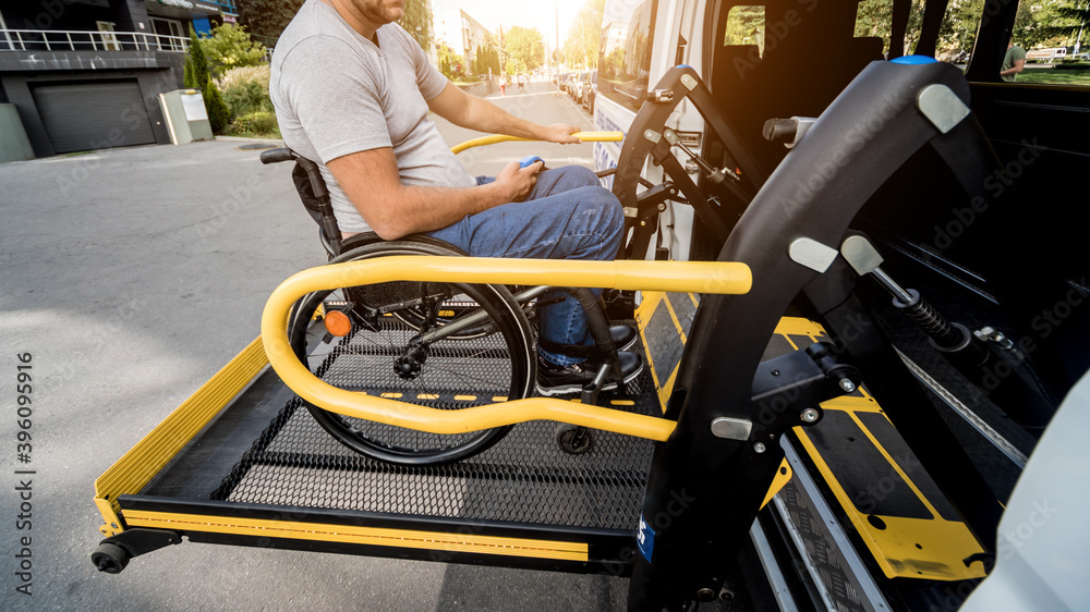 A man in a wheelchair on a lift of a vehicle for people with ...