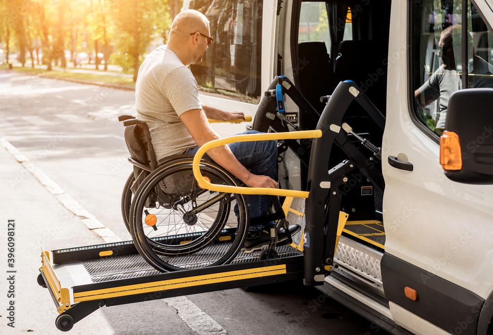A man in a wheelchair on a lift of a vehicle for people with ...