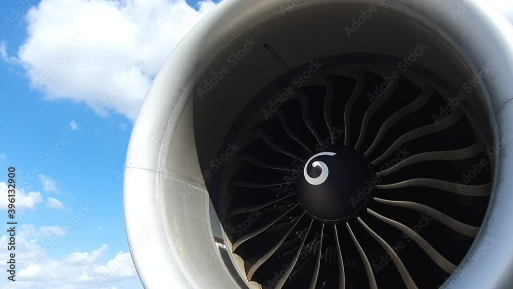 Jet turbine engine of aircraft rotating by wind with clouds and blue ...