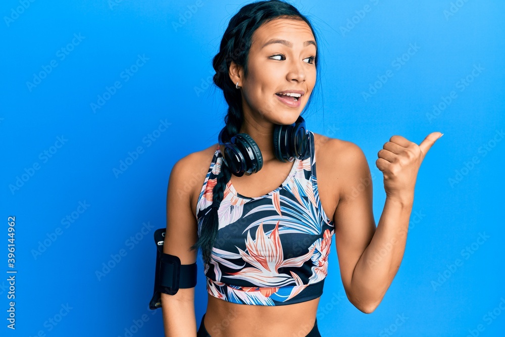 Beautiful hispanic woman wearing gym clothes and using headphones ...