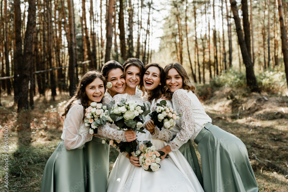 happy bride with cheerful bridesmaids hugging in beautiful dresses in ...