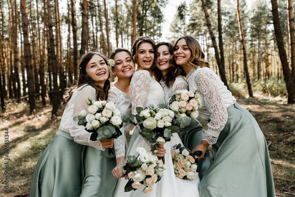happy bride with cheerful bridesmaids hugging in beautiful dresses in ...