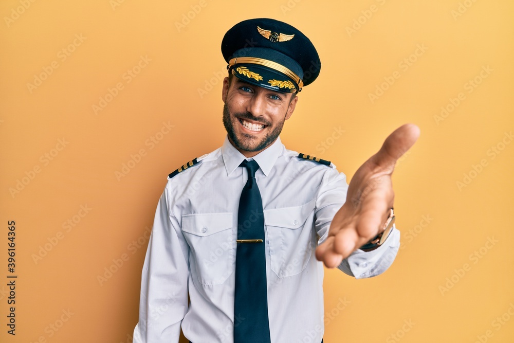 Handsome hispanic man wearing airplane pilot uniform smiling friendly ...