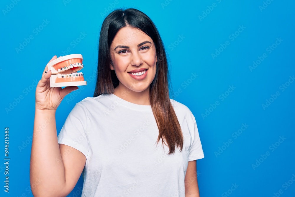 Young beautiful brunette woman asking for dental care holding denture ...