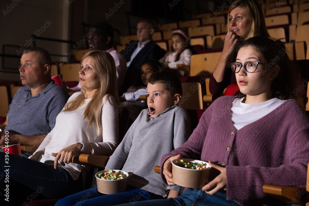 Portrait of scared and shocked adults and children watching scary movie ...