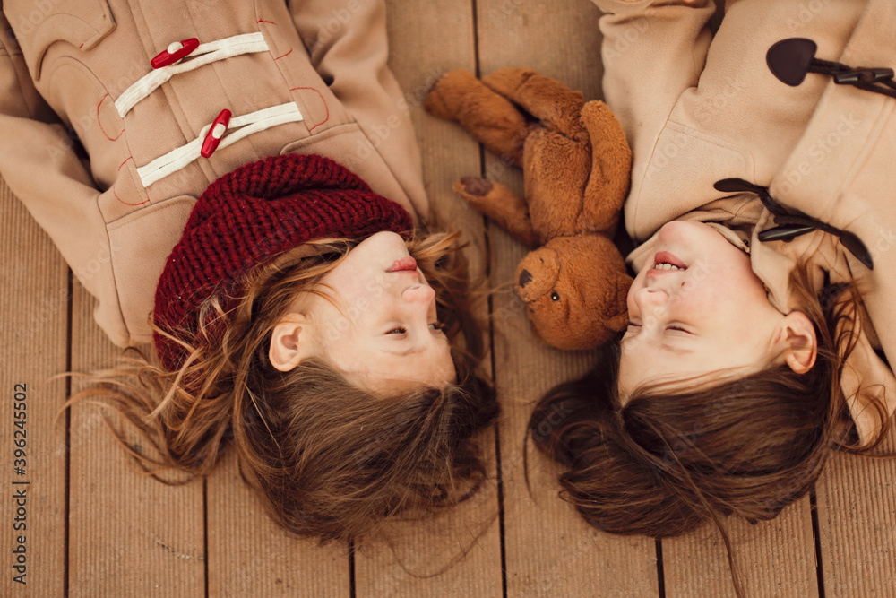 Two girls children lie dream by the lake with a soft toy teddy bear ...