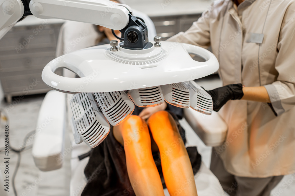 Woman doing led light therapy on her legs at luxury medical office ...