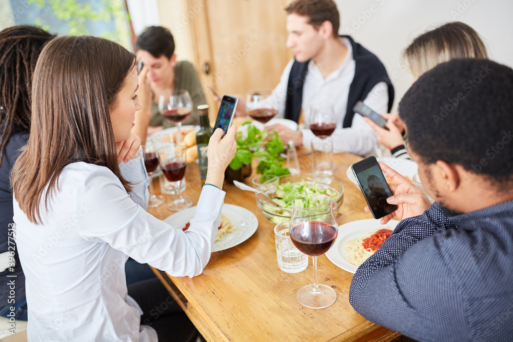 Distracted friends look at smartphone at lunch at the table Stock Photo ...