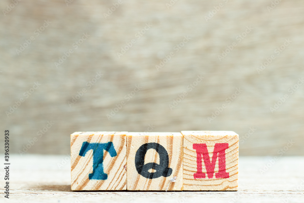 Alphabet letter block in word TQM (Abbreviation of total quality management) on wood background ...