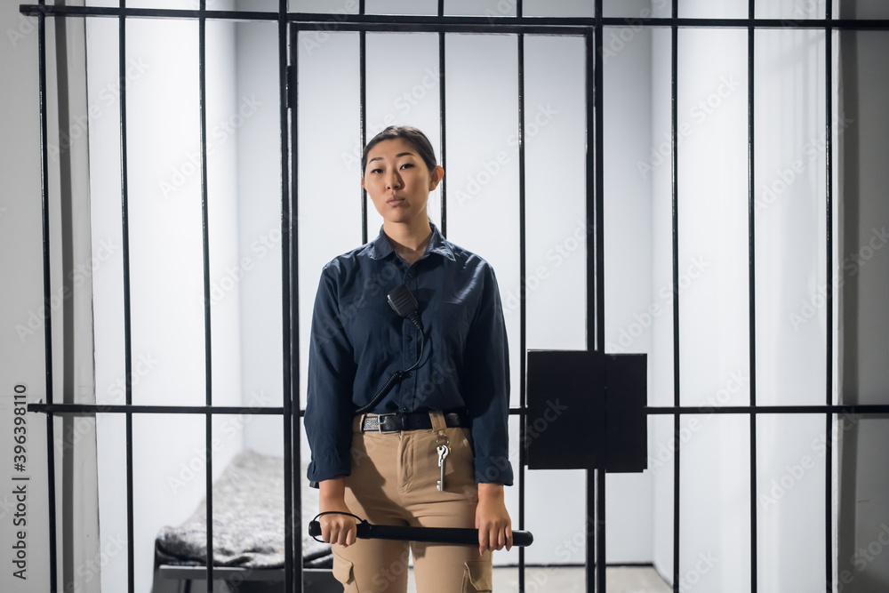 Foto de A young prison guard poses in front of prison bars in uniform ...