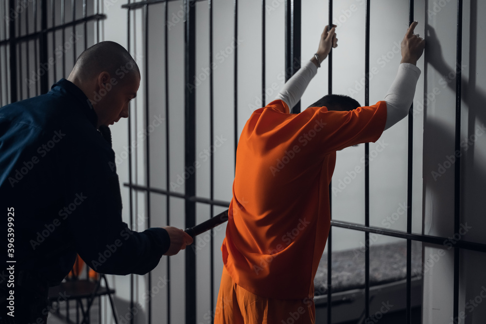 Stockfoto An armed guard searches a newly arrived criminal in a prison ...