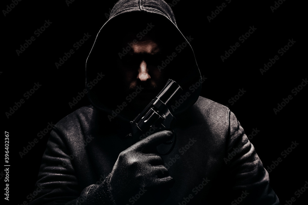 Photo of a creepy horror criminal in black hoodie holding revolver gun ...