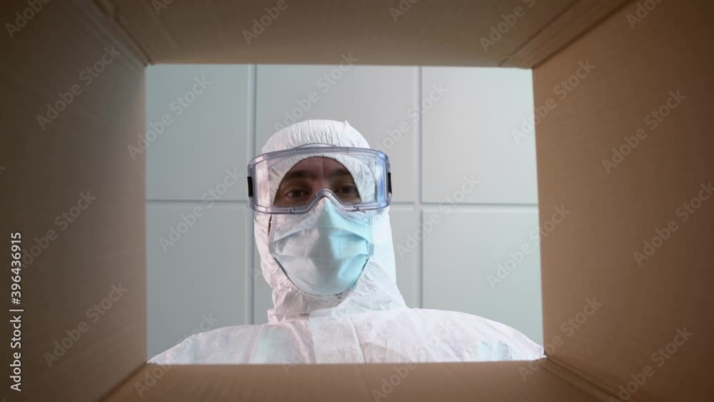 Healthcare worker in personal protective equipments packing a box of ...