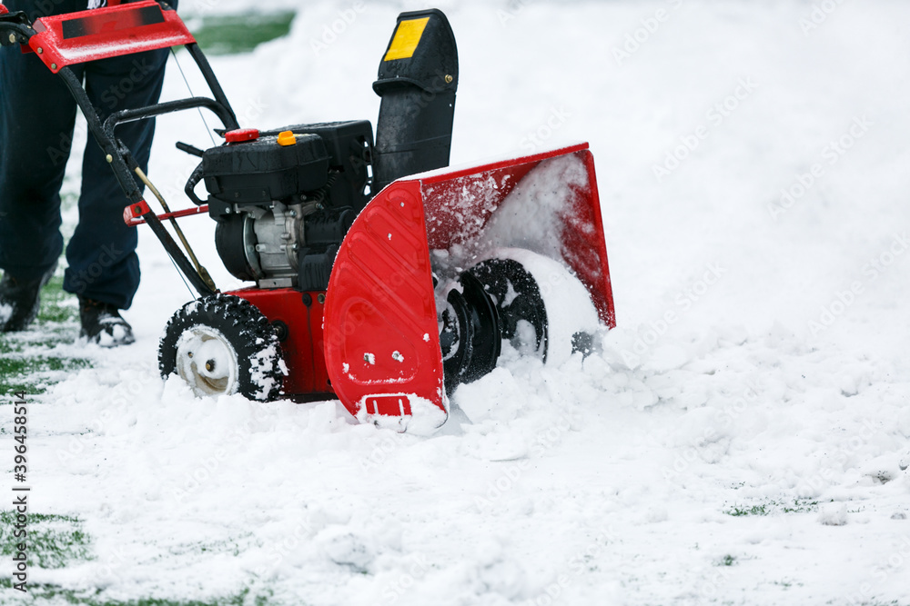 Foto de Man using a snow blower to remove large amounts of snow on football field. Man cleans ...