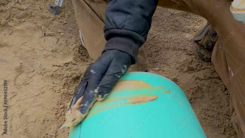 Construction worker spreading pipe lube / grease on the end of a sewer ...