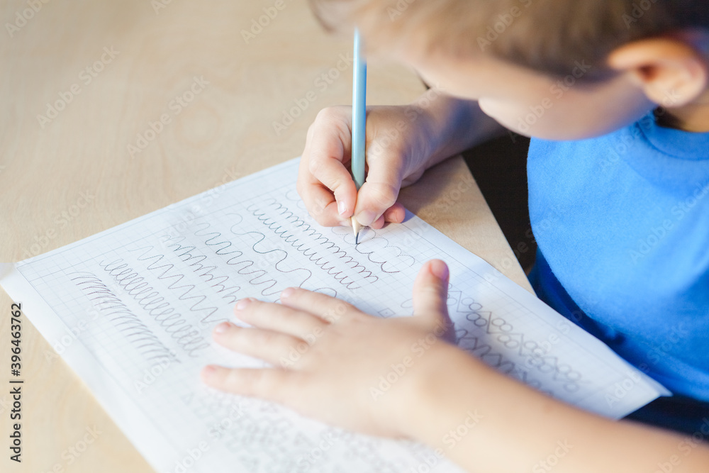 Kid doing lesson at home. Child boy writing in worksheet with pencil ...