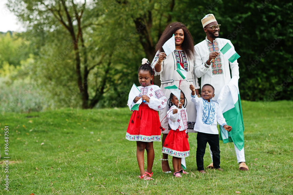 African family in traditional clothes with nigerian flags at park ...
