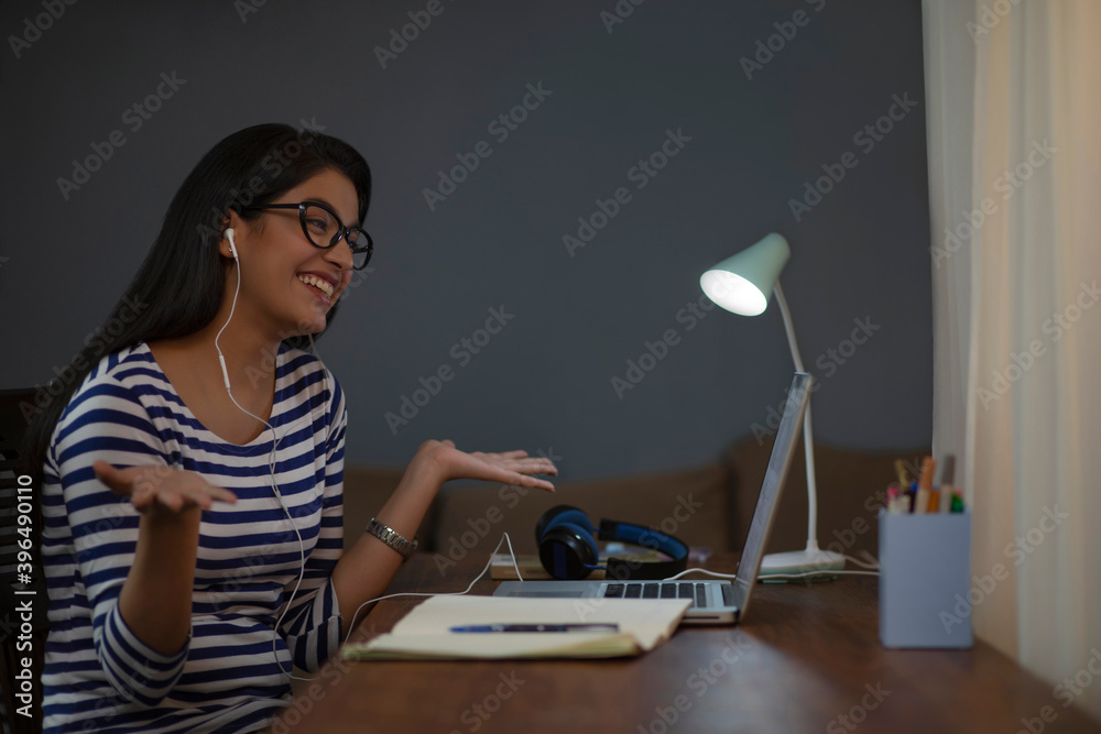Girl talking on a video call late at night while completing her ...