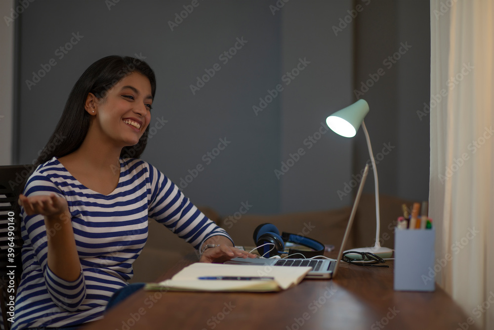 Girl talking on a video call late at night while completing her ...
