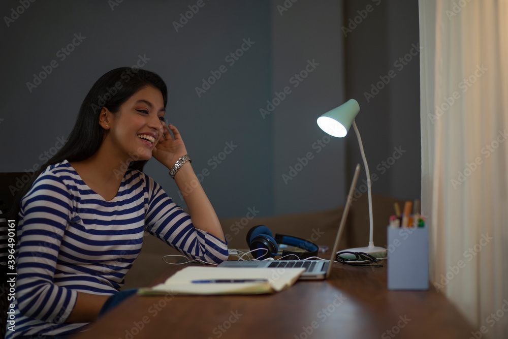 Girl talking on a video call late at night while completing her ...