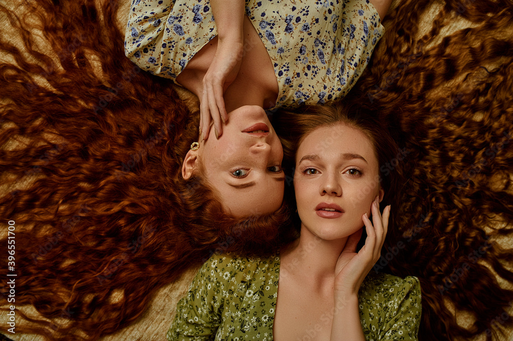 Two beautiful models, friends, sisters with long natural curly hair lay ...