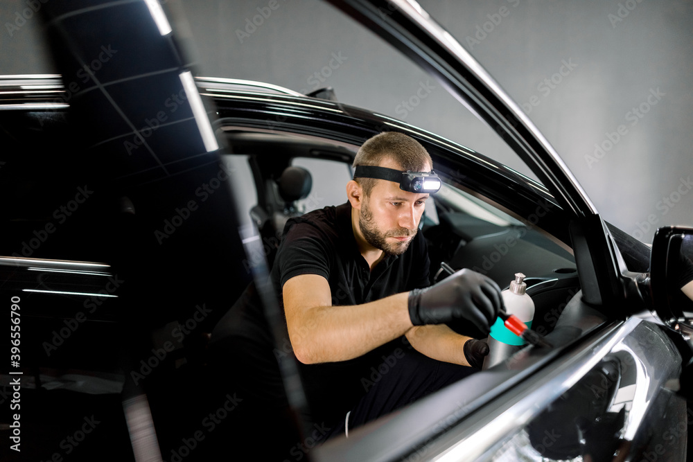 Young auto service station male worker, wearing uniform and gloves ...