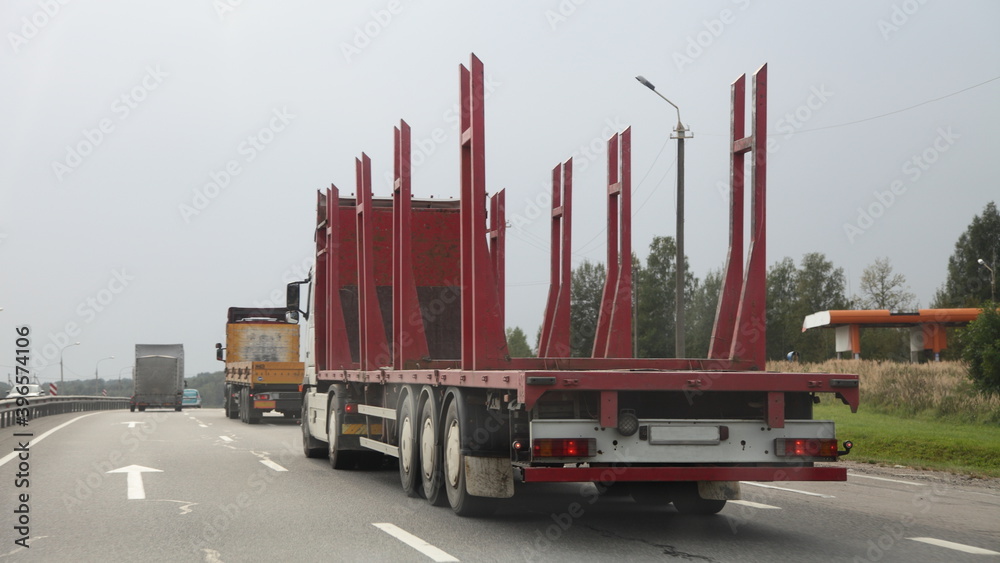 Empty wood truck drive with a red semi trailer drive on a suburban ...