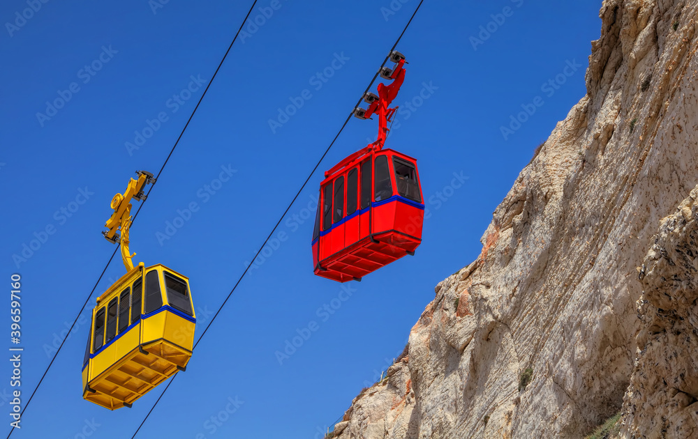 Cableway cabins against bright blue sky and white chalk cliff ...