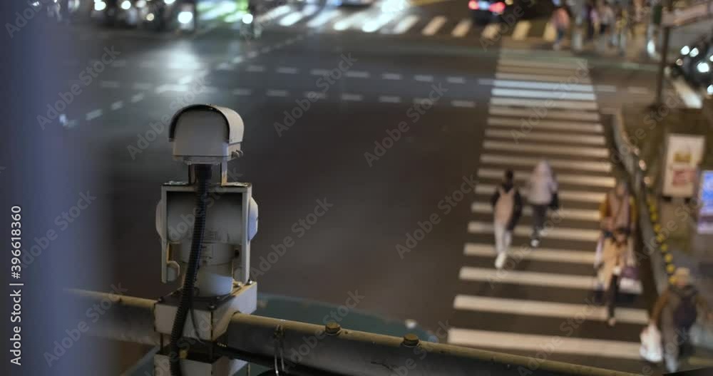 A security CCTV camera at pedestrian crossing on busy street at night ...