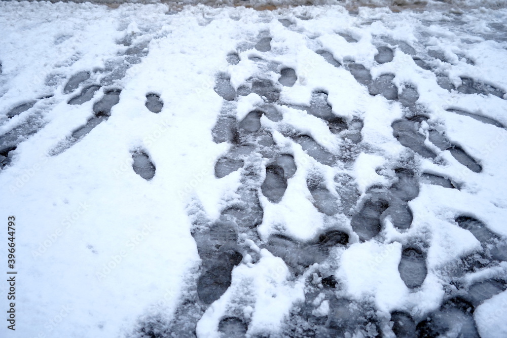 Street covered with snow and imprints of the shoes of the passers by ...