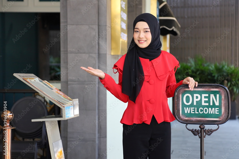 Muslim lady standing outside the halal restaurant with open sign to ...