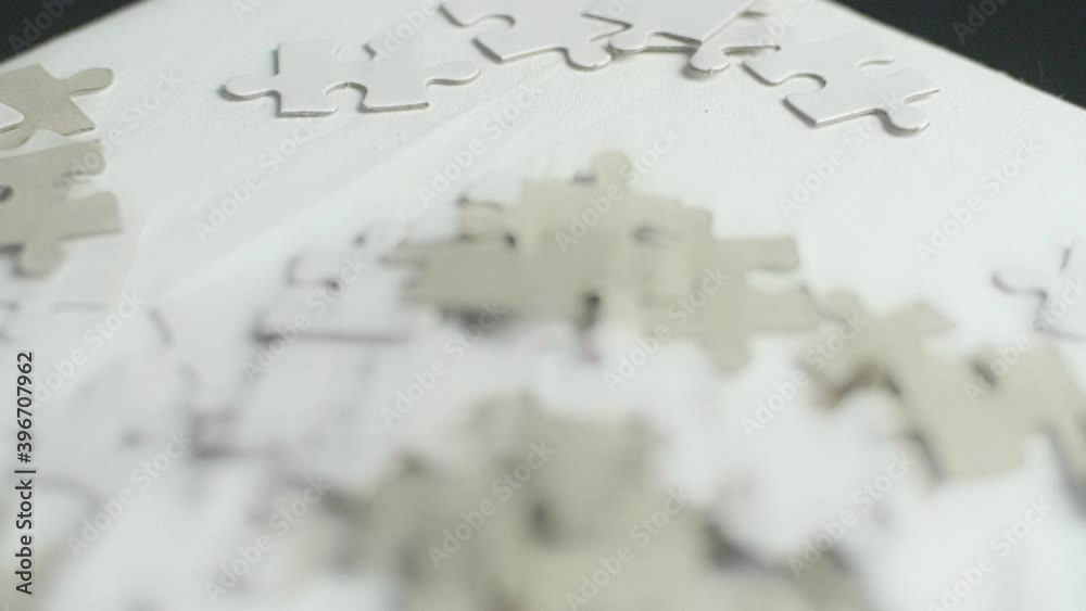 White and gray puzzle pieces laying randomly on a white surface with a ...