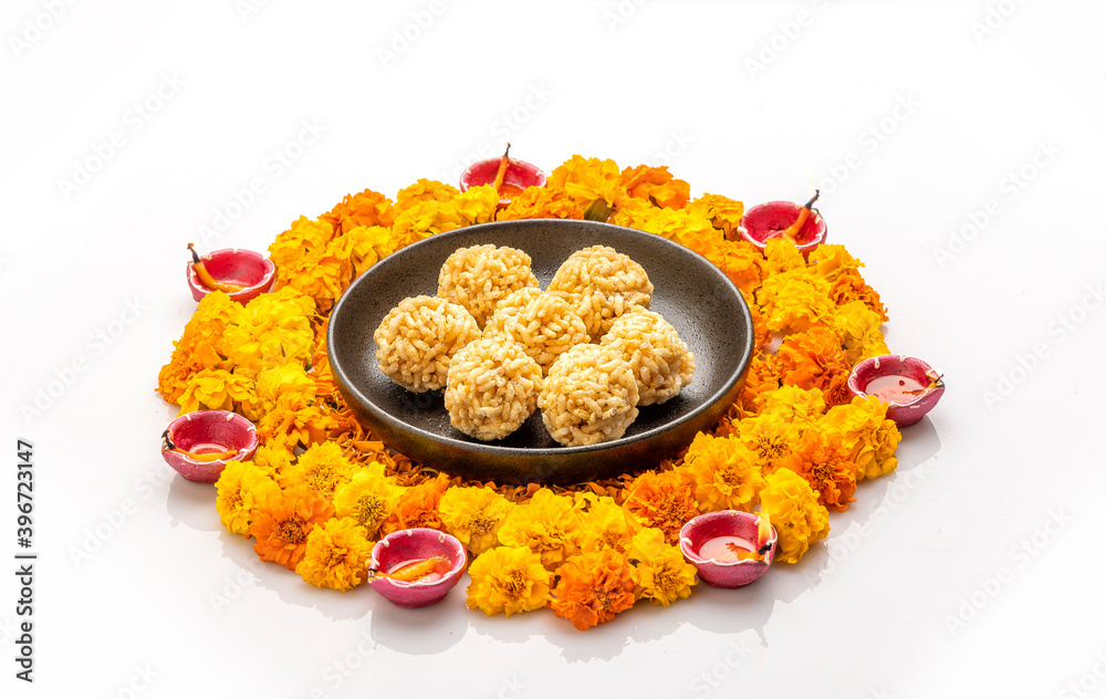 puffed rice balls in a plate kept on Rangoli design made with flower ...