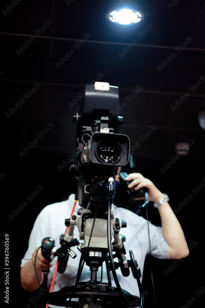 Cameraman standing behind a professional TV-camera on a tripod, with ...