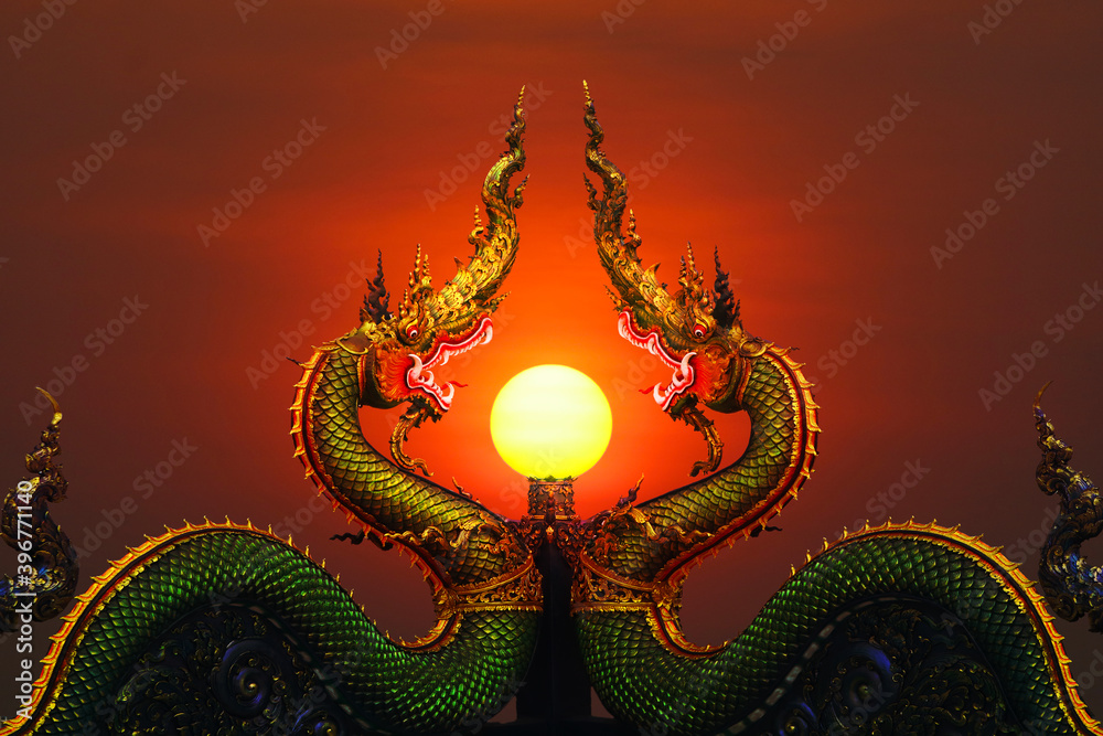 Two Naga status and pole in middle and sunset red sky on top of pole ...