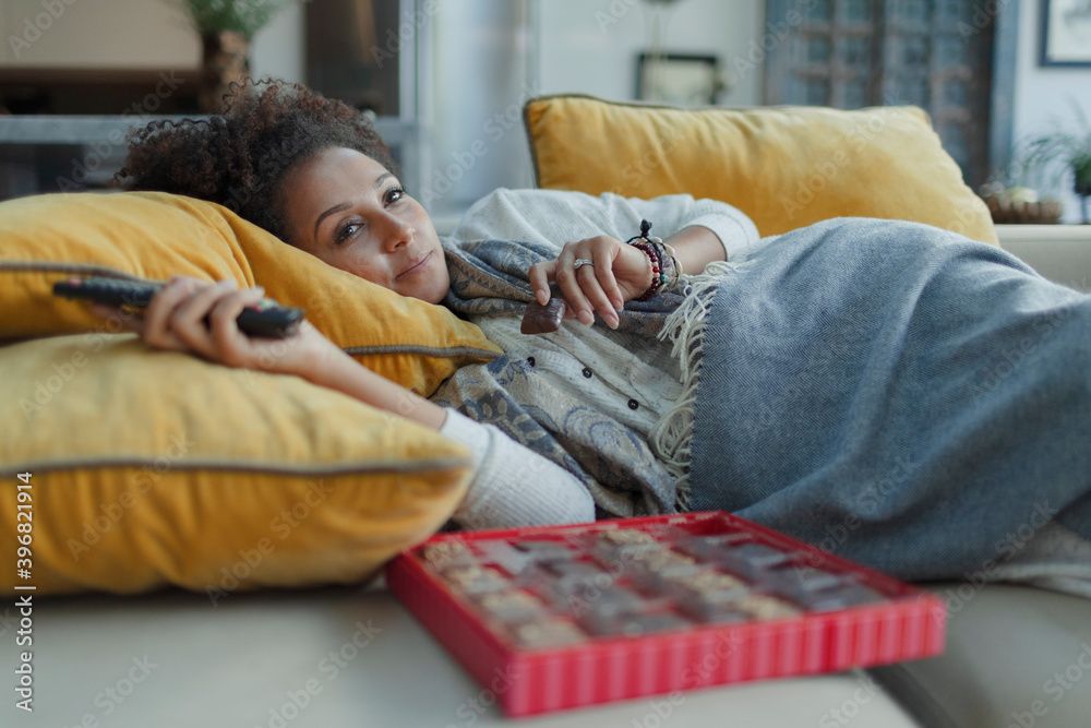 Cozy woman eating chocolates and watching TV on living room sofa Stock ...