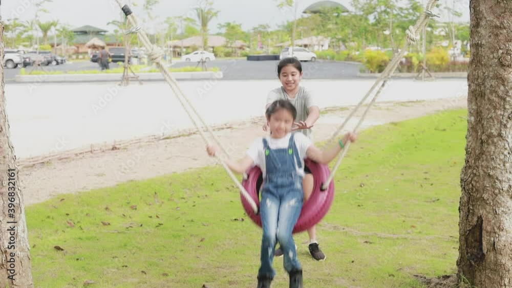 HD Happy asian girls play swing at park together. Two sisters have fun ...