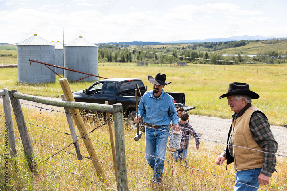 Multigenerational ranchers fixing fence on sunny rural ranch Stock ...